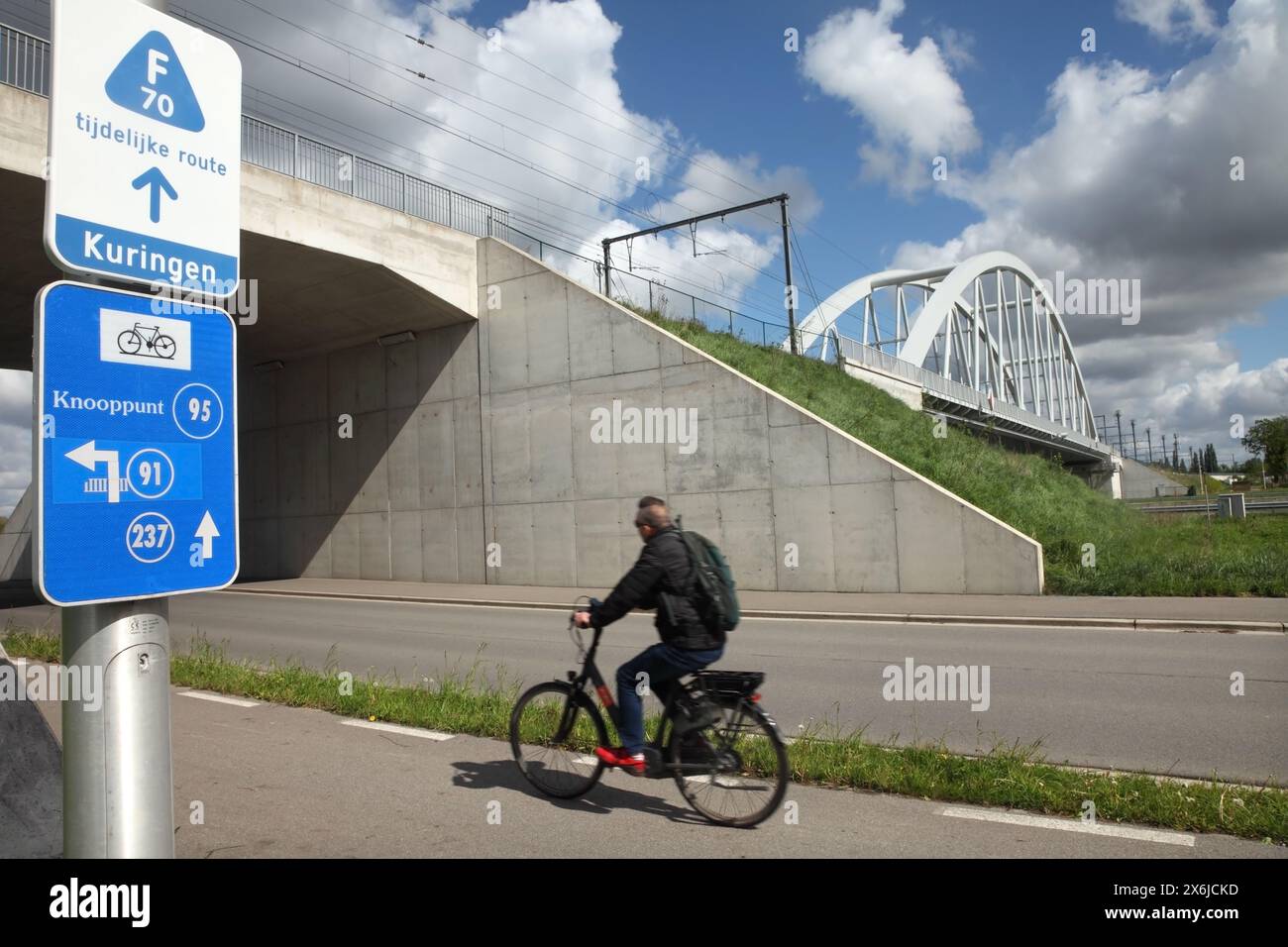 Cyclist using cycle route passing under railway bridge over the Albert ...