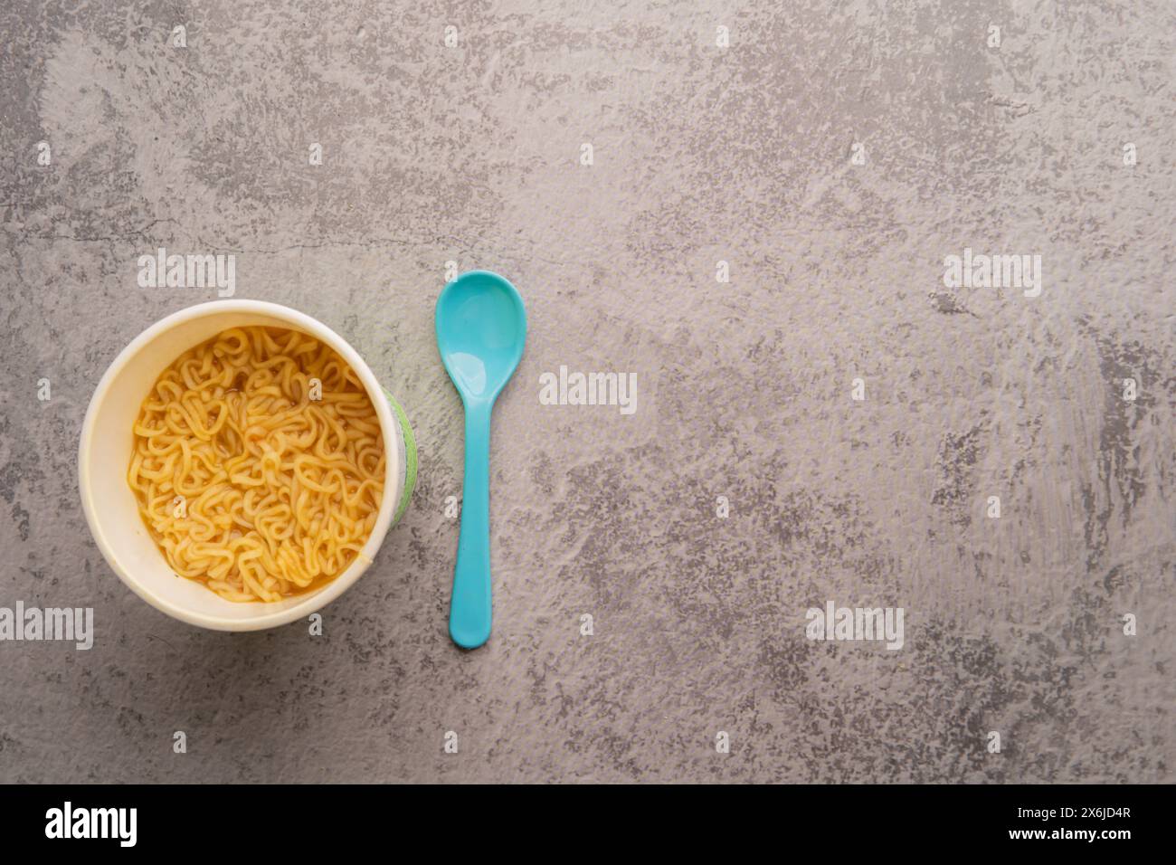Overview of a bowl of instant pasta soup with a spoon a light gray ...