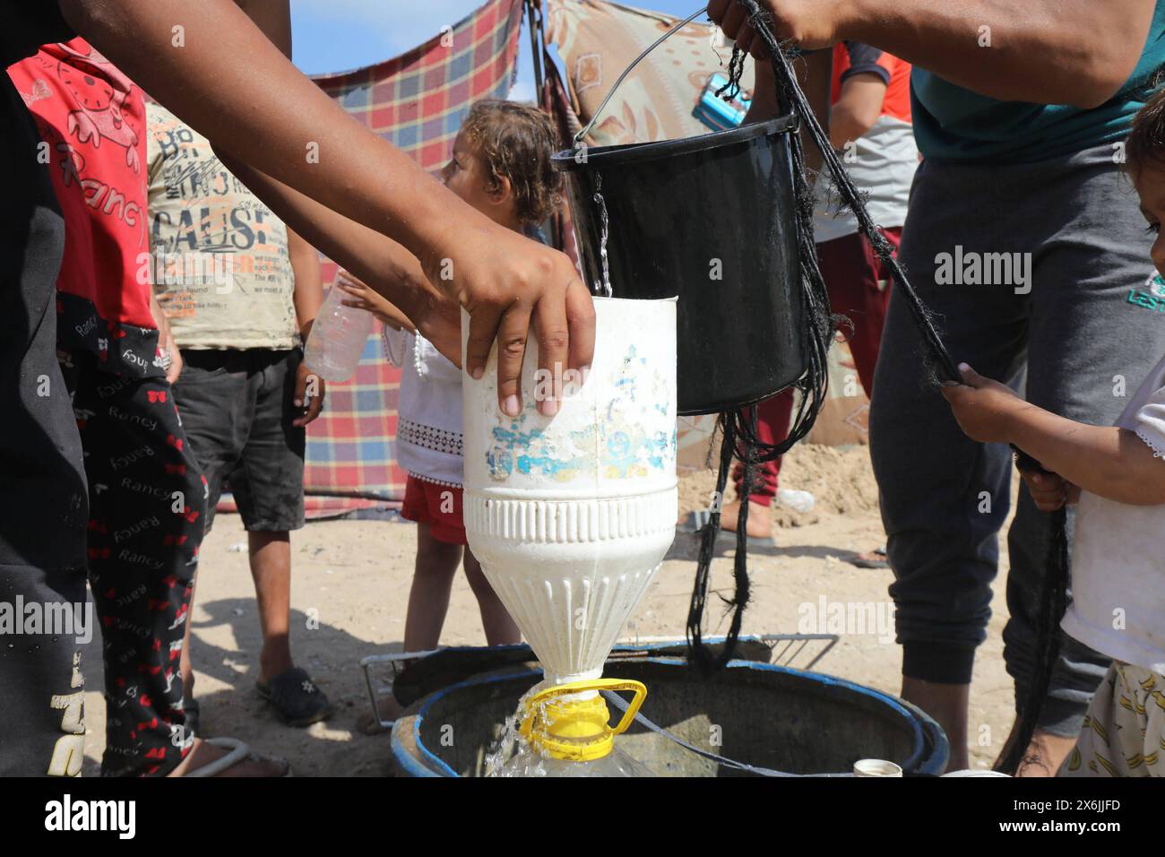 Displaced Palestinians wait to get water from a traditional water well ...