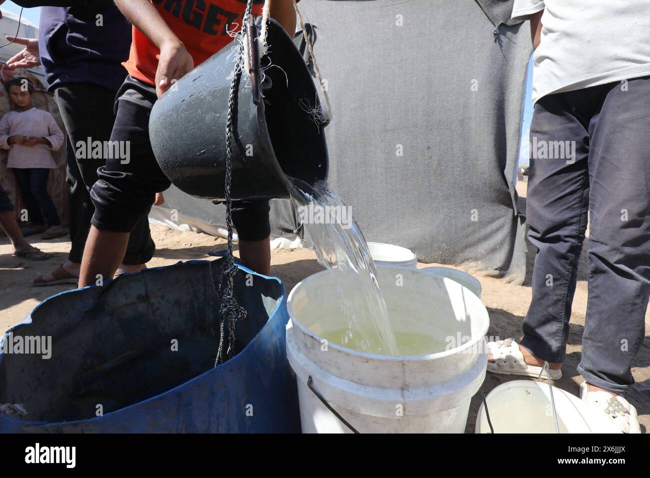 Displaced Palestinians wait to get water from a traditional water well ...