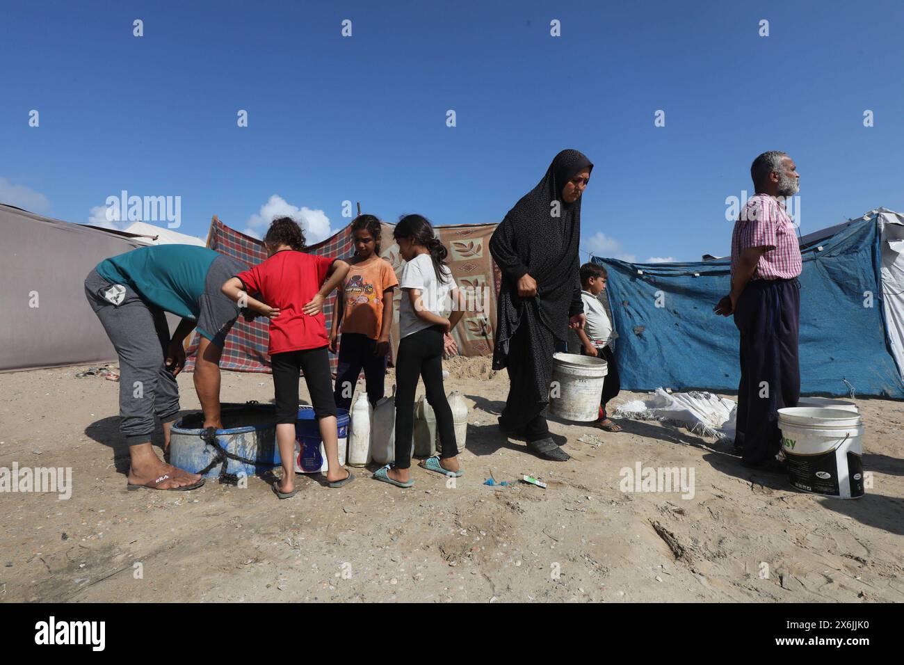 Displaced Palestinians wait to get water from a traditional water well ...