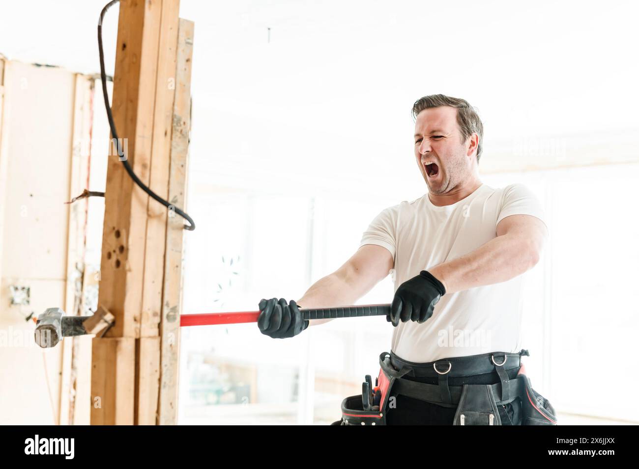 builder carpenter with sledge hammer hit a wall with frustration Stock ...