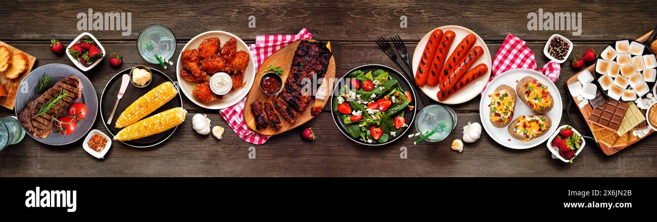Summer BBQ food table scene over a dark wood banner background ...