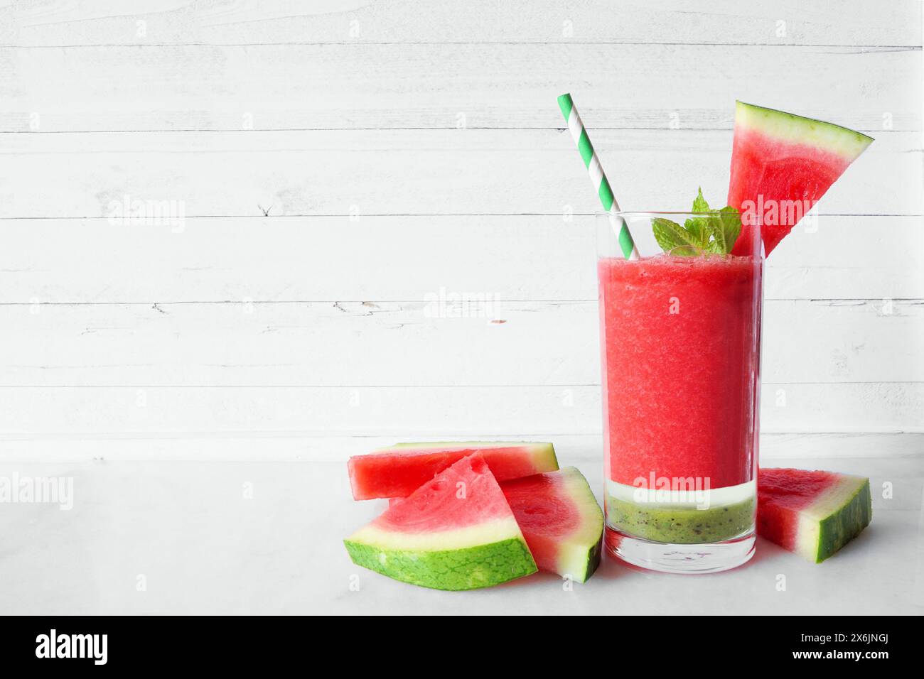 Refreshing layered watermelon drink. Side view against a white wood ...