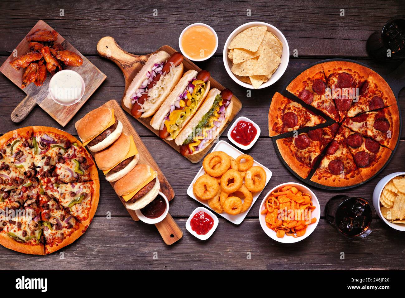 Junk food table scene. Pizza, hamburgers, chicken wings, hot dogs and ...