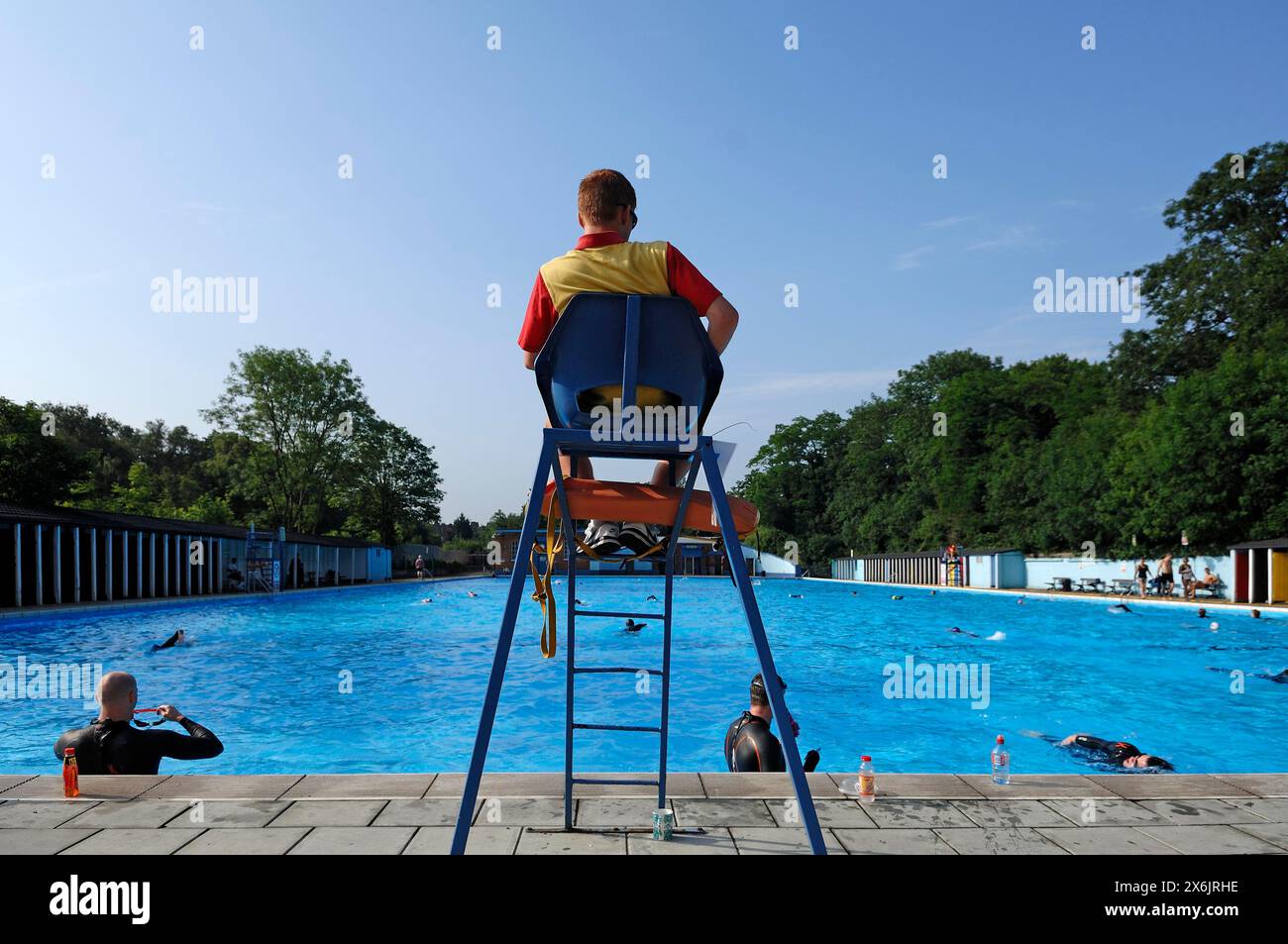 Lifeguard on duty in the high seat at the large outdoor swimming pool ...