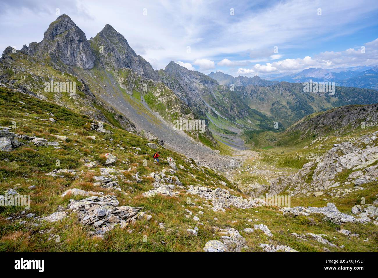 Mountaineer on a hiking trail at a saddle, pointed rocky mountain peaks ...