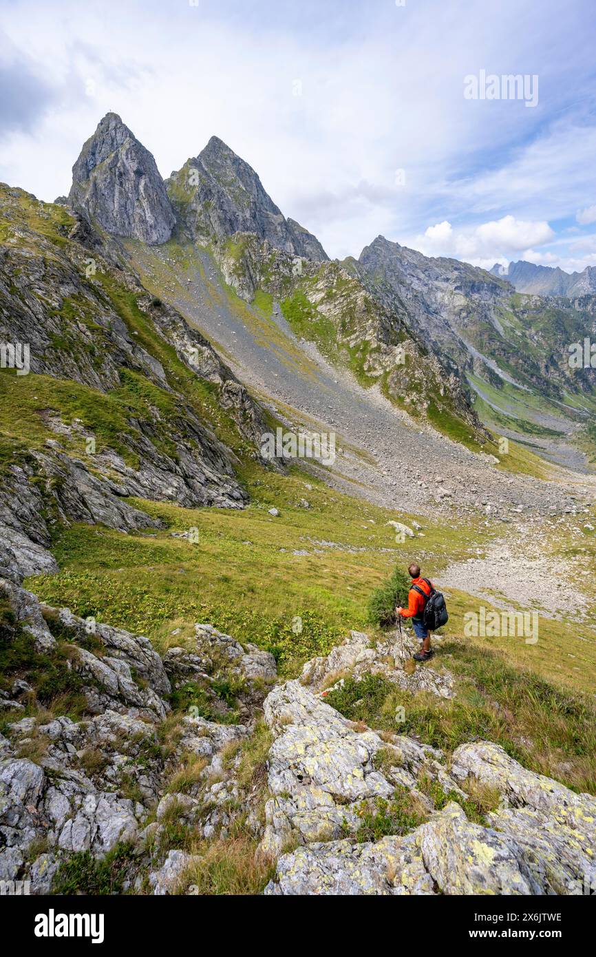 Mountaineer on a hiking trail at a saddle, pointed rocky mountain peaks ...