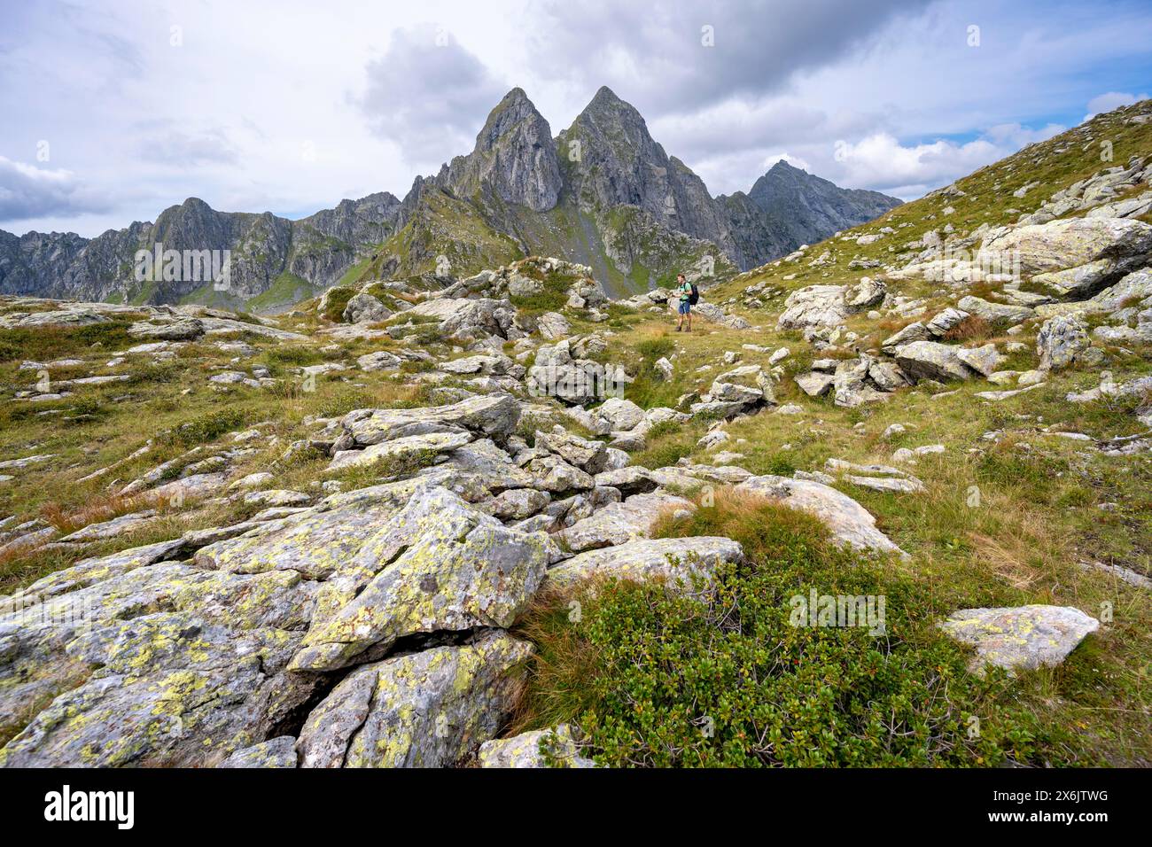 Mountaineer on a hiking trail at a saddle, pointed rocky mountain peaks ...