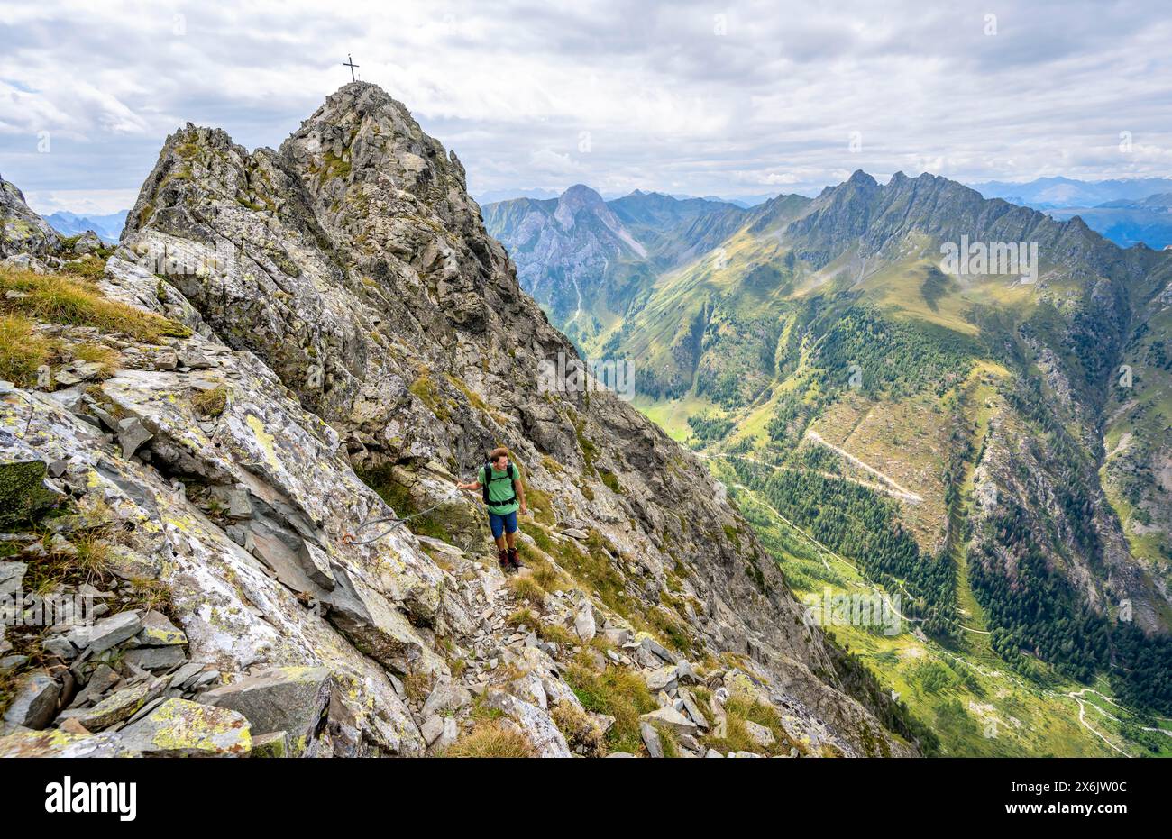 Mountaineer on a narrow mountain path, rocky pointed summit of the ...
