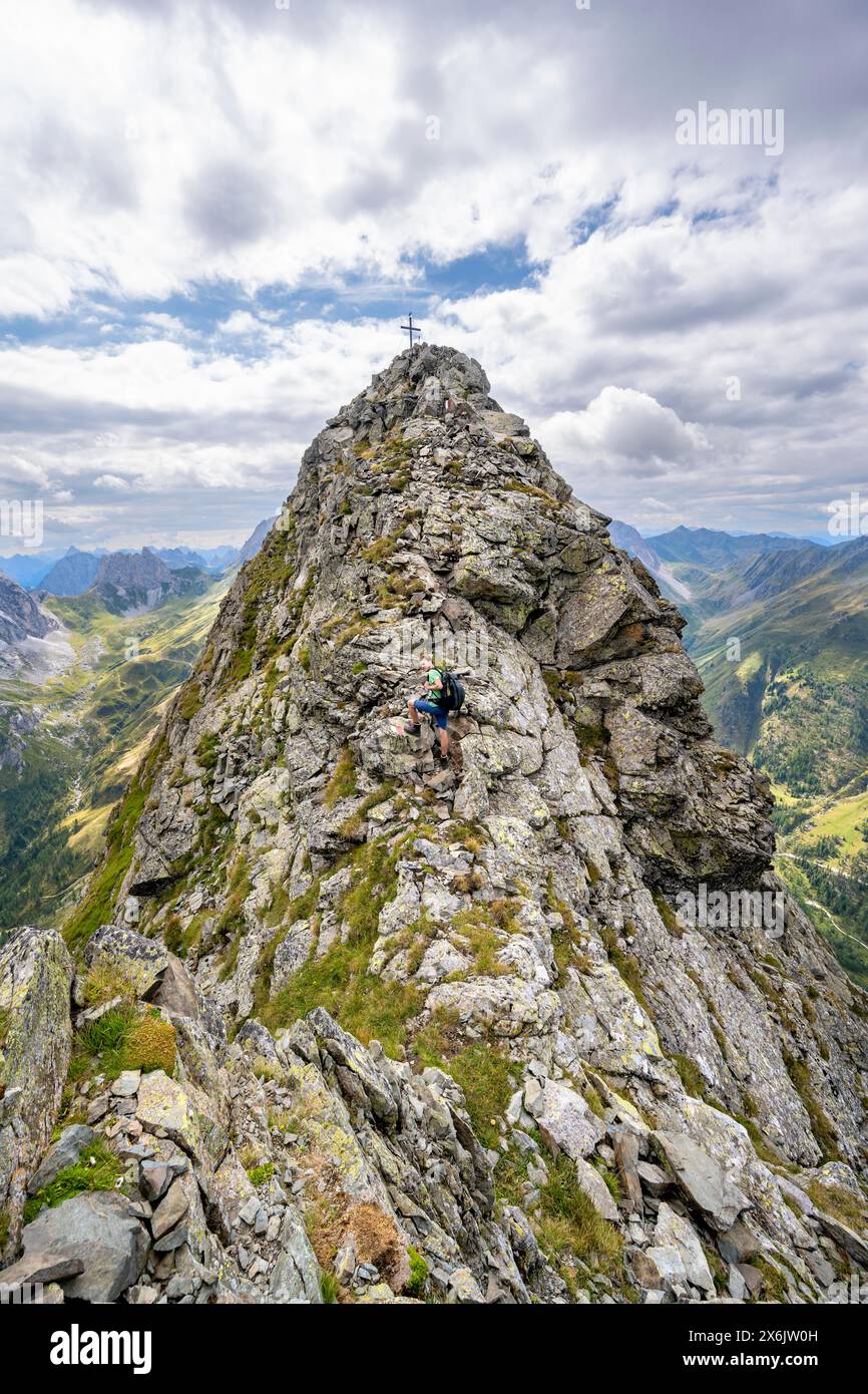 Mountaineer on a narrow mountain path, rocky pointed summit of the ...