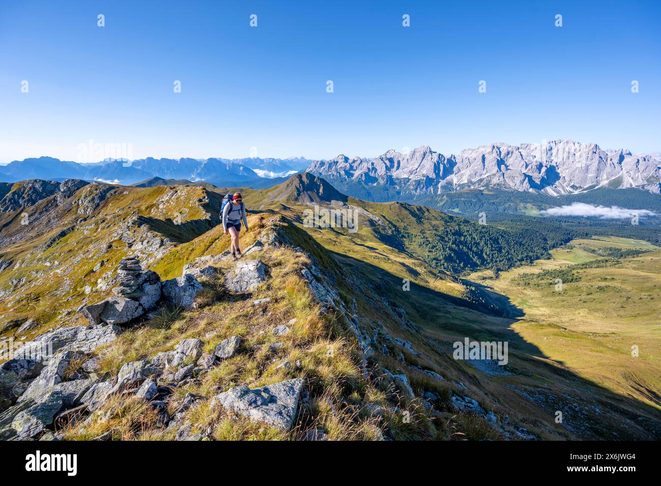 Mountaineer on a grassy ridge, mountain panorama, view of rocky ...