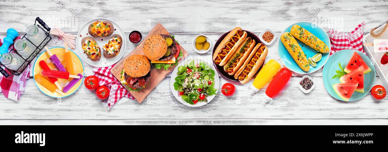 Summer BBQ food table scene. Hamburgers, hot dogs, potatoes, corn and ...