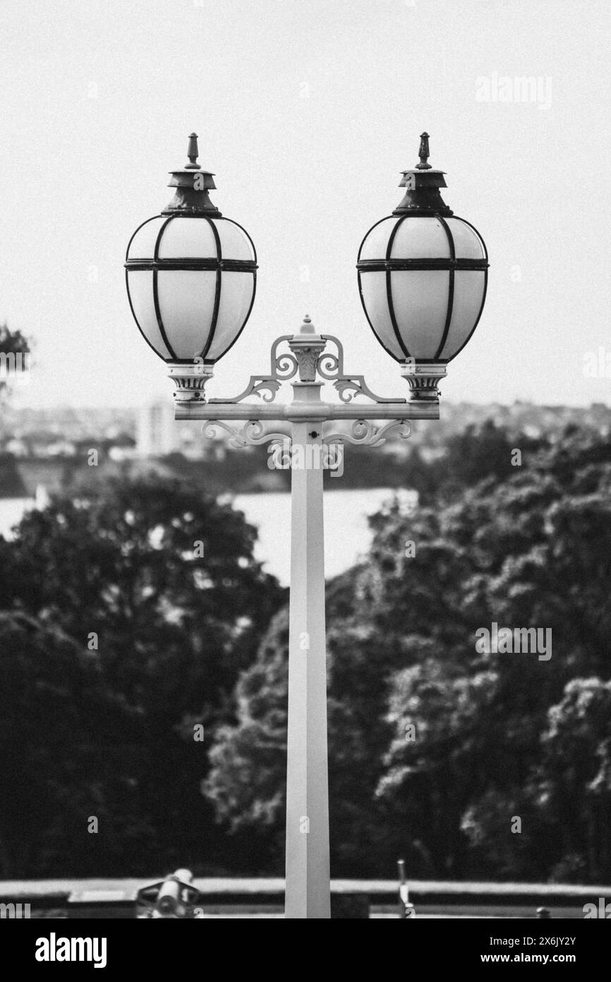 Old lamps light up the park in the evening with a view of the bay and ...