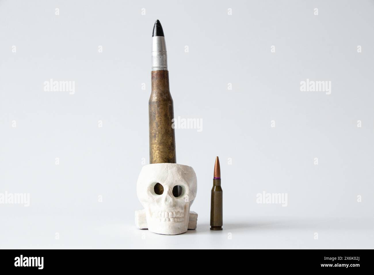 Two bullets, large and small, and a plaster skull on a white background ...