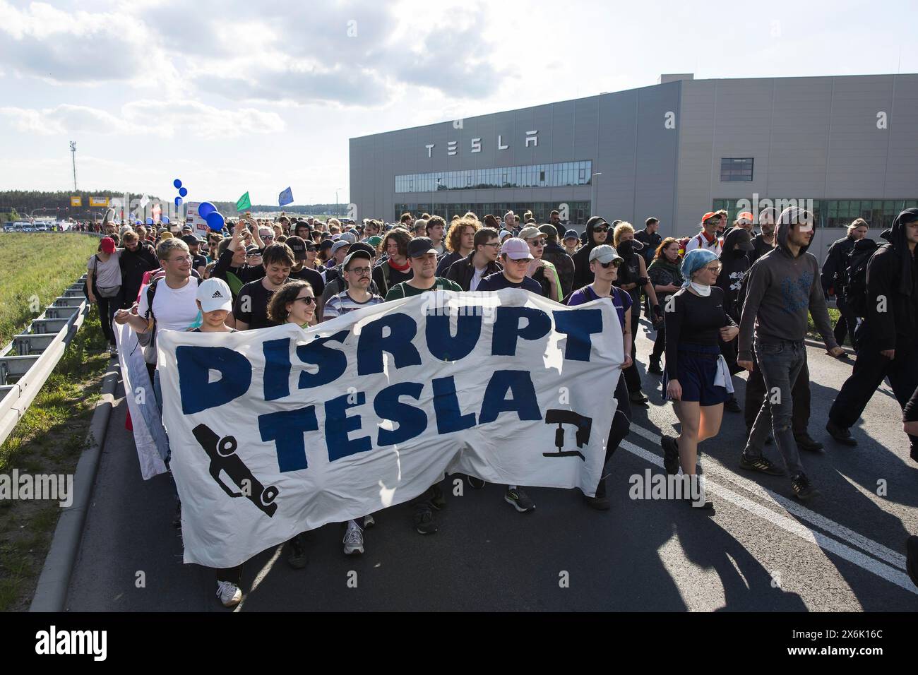 Participants with banner Disrupt Tesla in front of the Tesla ...