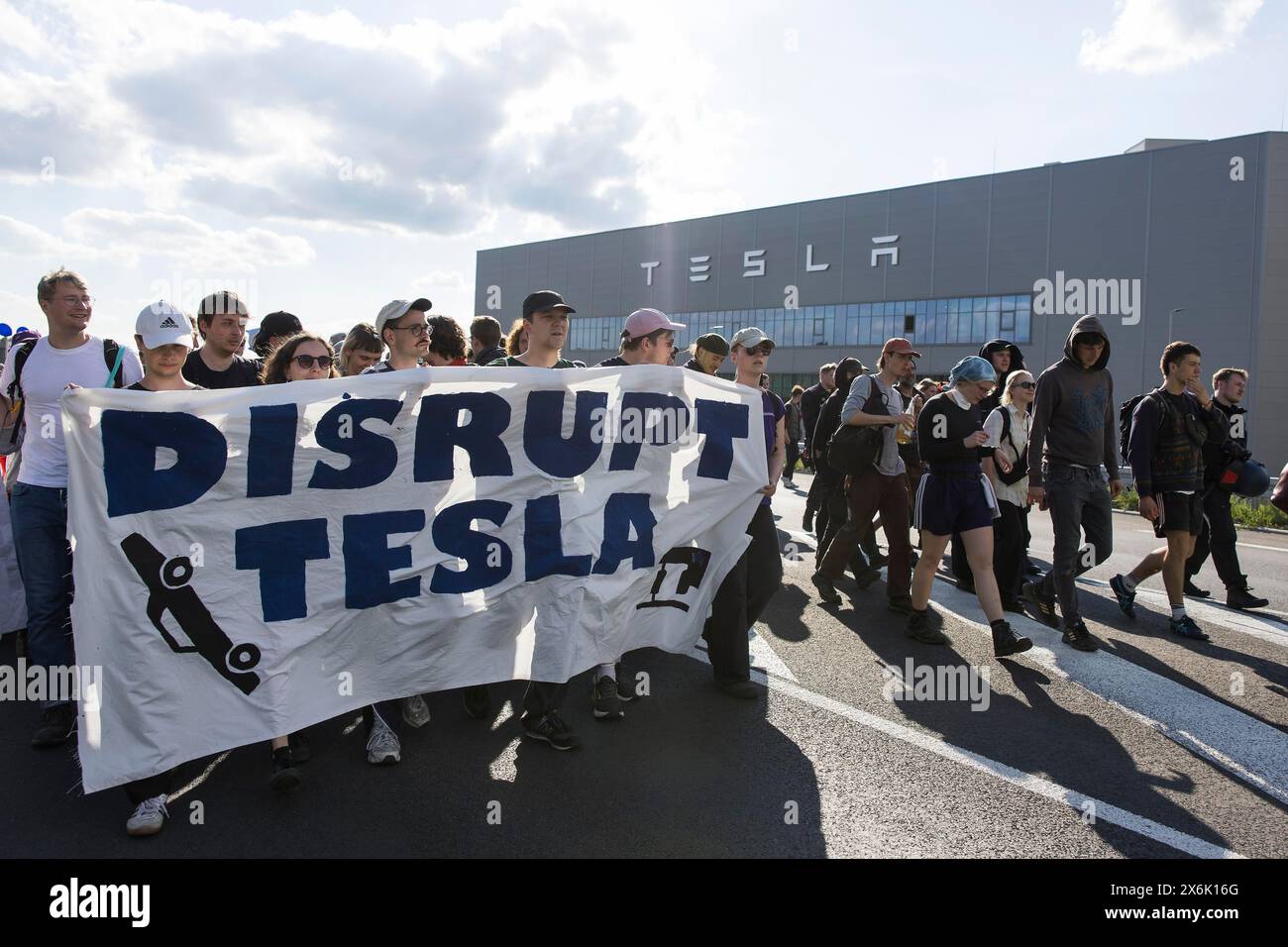 Participants with banner Disrupt Tesla in front of the Tesla ...