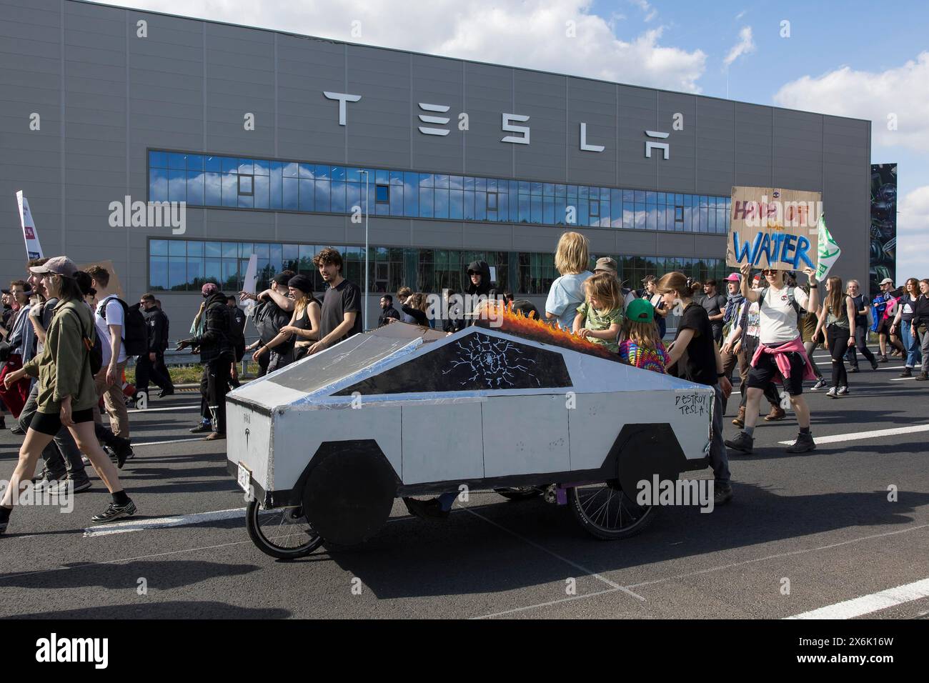 Participants with a Cybertruck cardboard model on a bicycle and sign ...