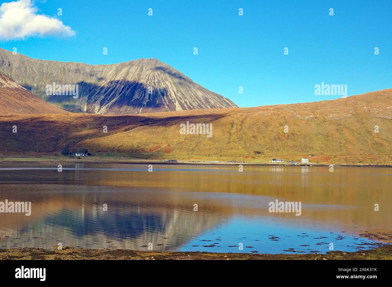 The rounded rugged mountains of the Cullins and two houses on an inlet ...