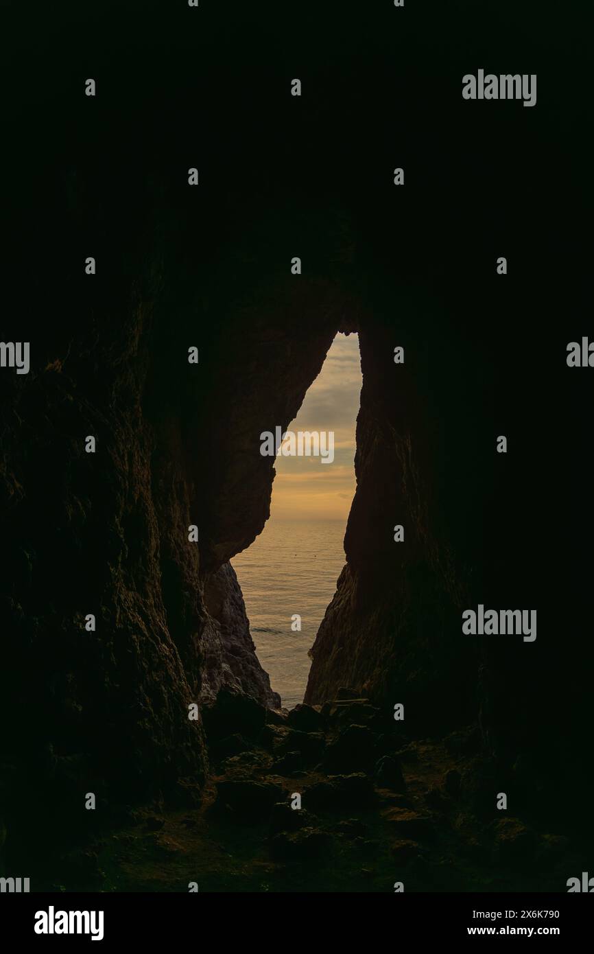 A cave with a small opening in the wall. The cave is dark and the sky ...