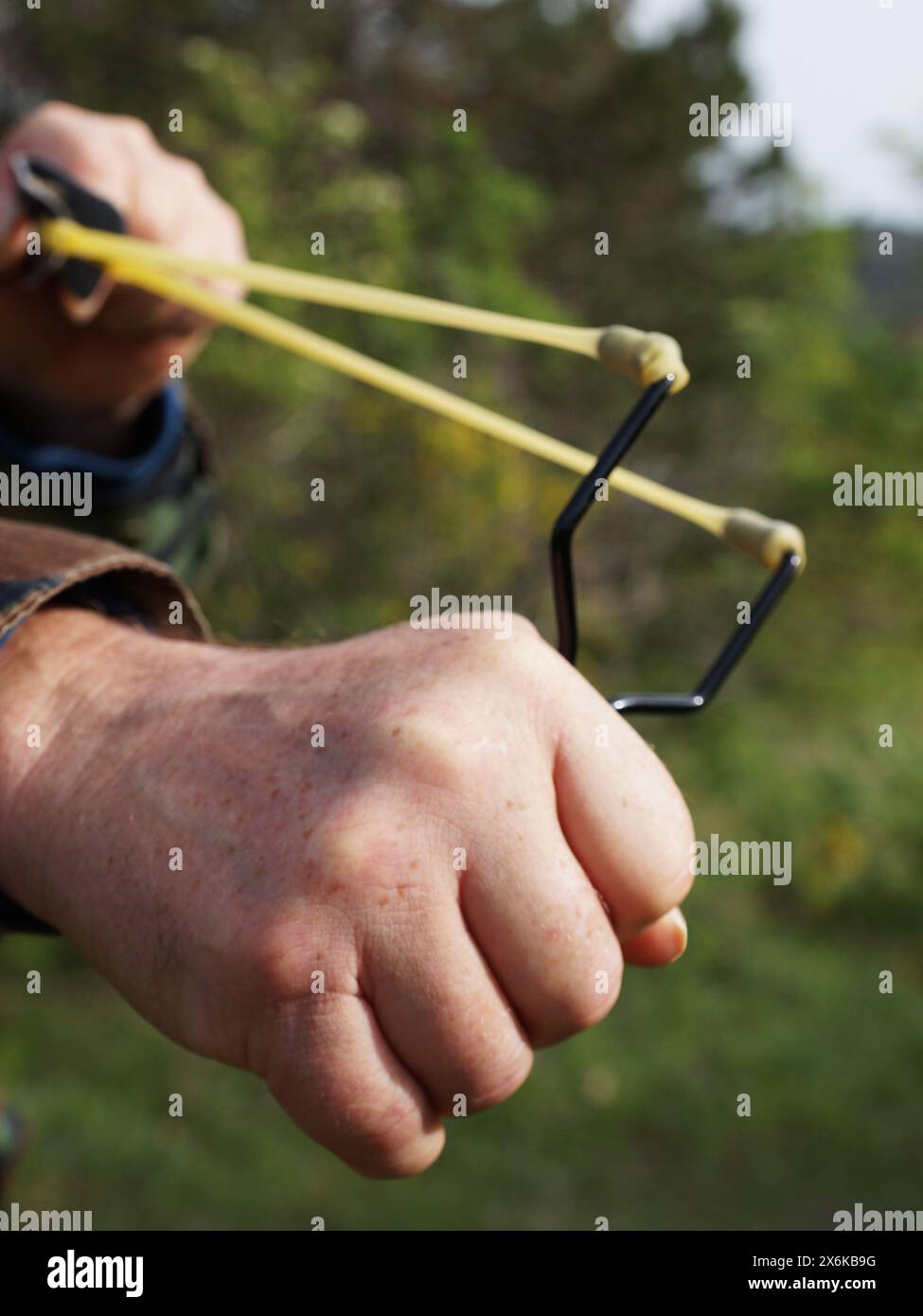 A man pulls the rubber band of a slingshot for a shot in the forest ...