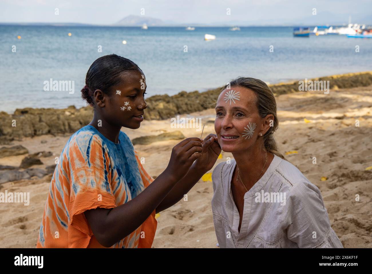 Local woman applies Masonjoany decorative face paint to a blonde ...