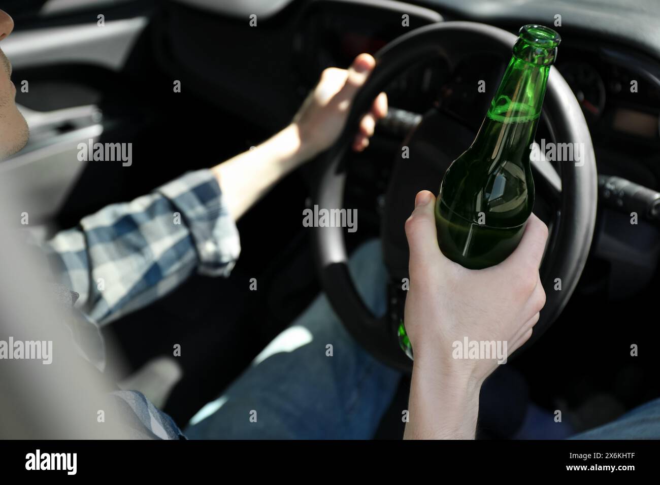 Man with bottle of beer driving car, closeup. Don't drink and drive ...