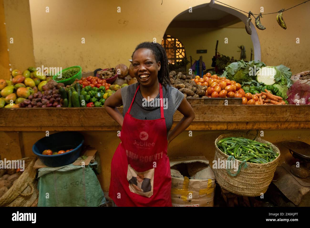 Happy woman at a fruit and vegetable stall in the market hall, Lamu ...
