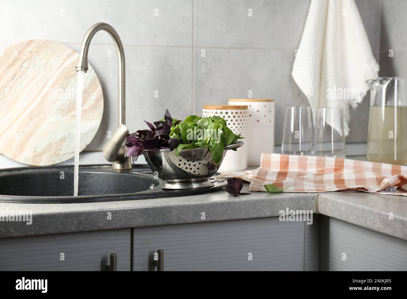 Metal colander with different fresh basil leaves on grey countertop ...