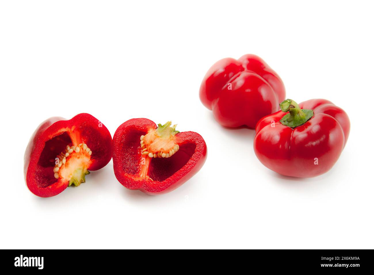 Two whole and halves of red bell pepper (capsicum) known as sweet bell ...
