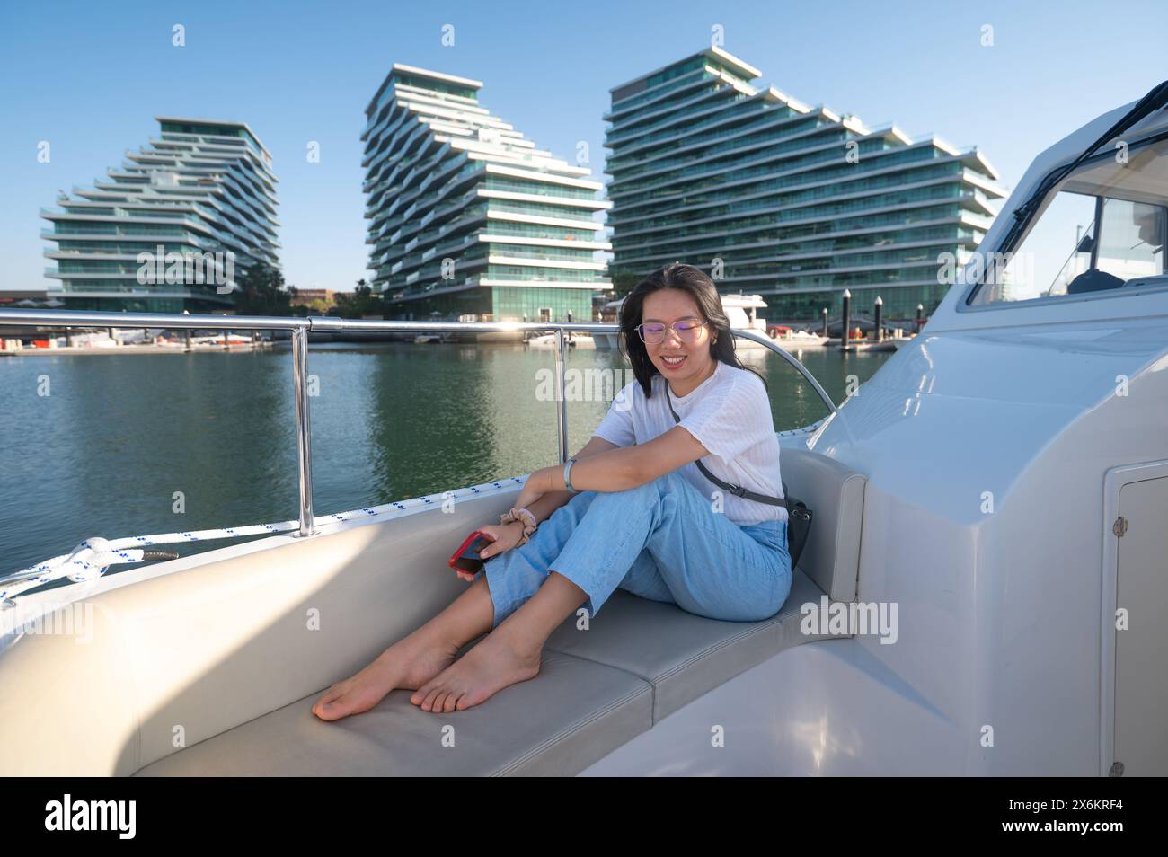 A smiling Asian woman is enjoying a sunny boat ride near the Al Raha ...