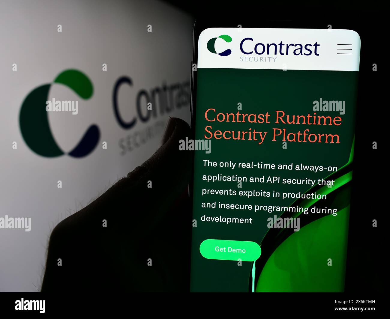 Person holding cellphone with webpage of US software company Contrast ...