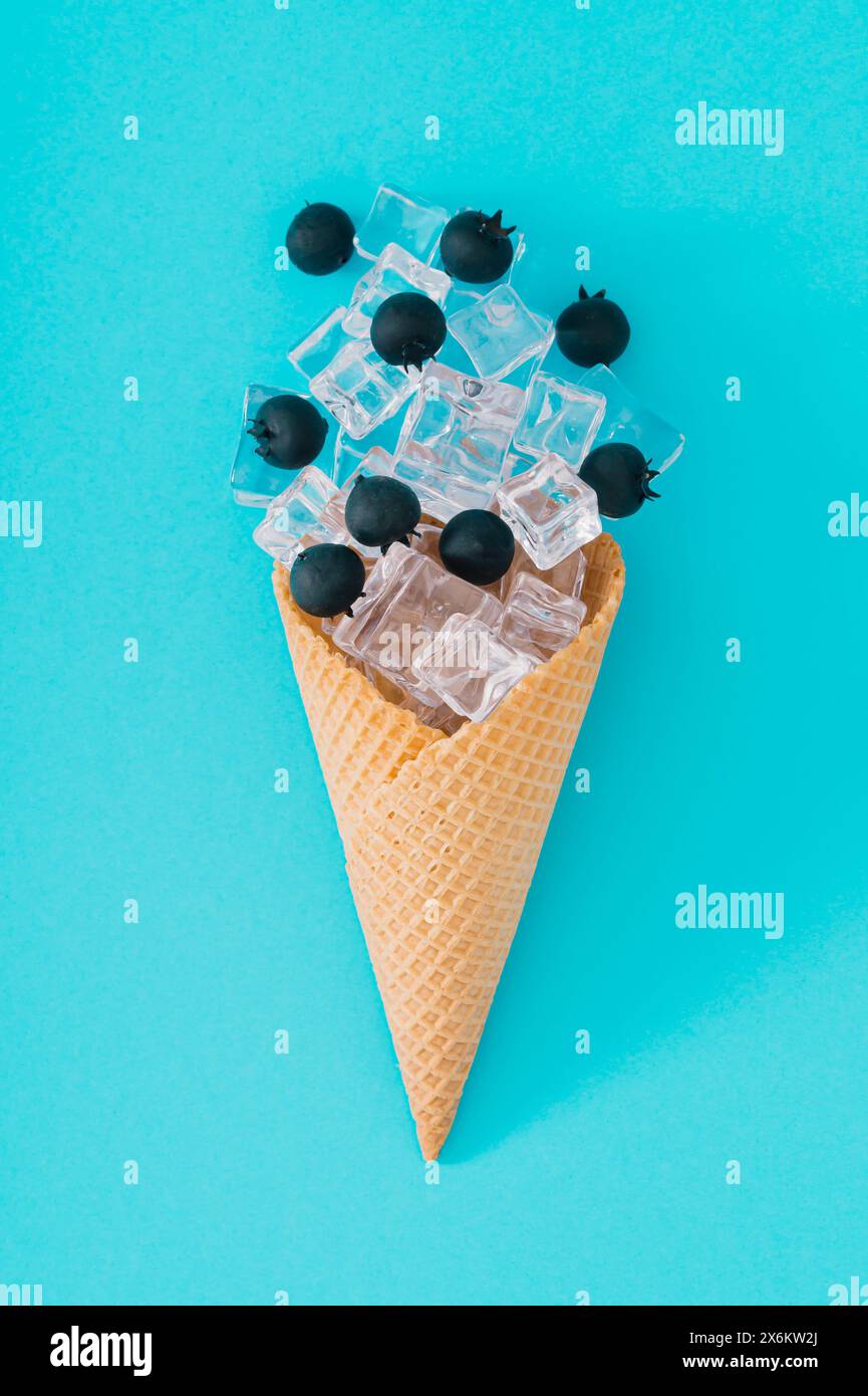 Ice cream cone with blueberries and ice cubes on aqua blue background ...