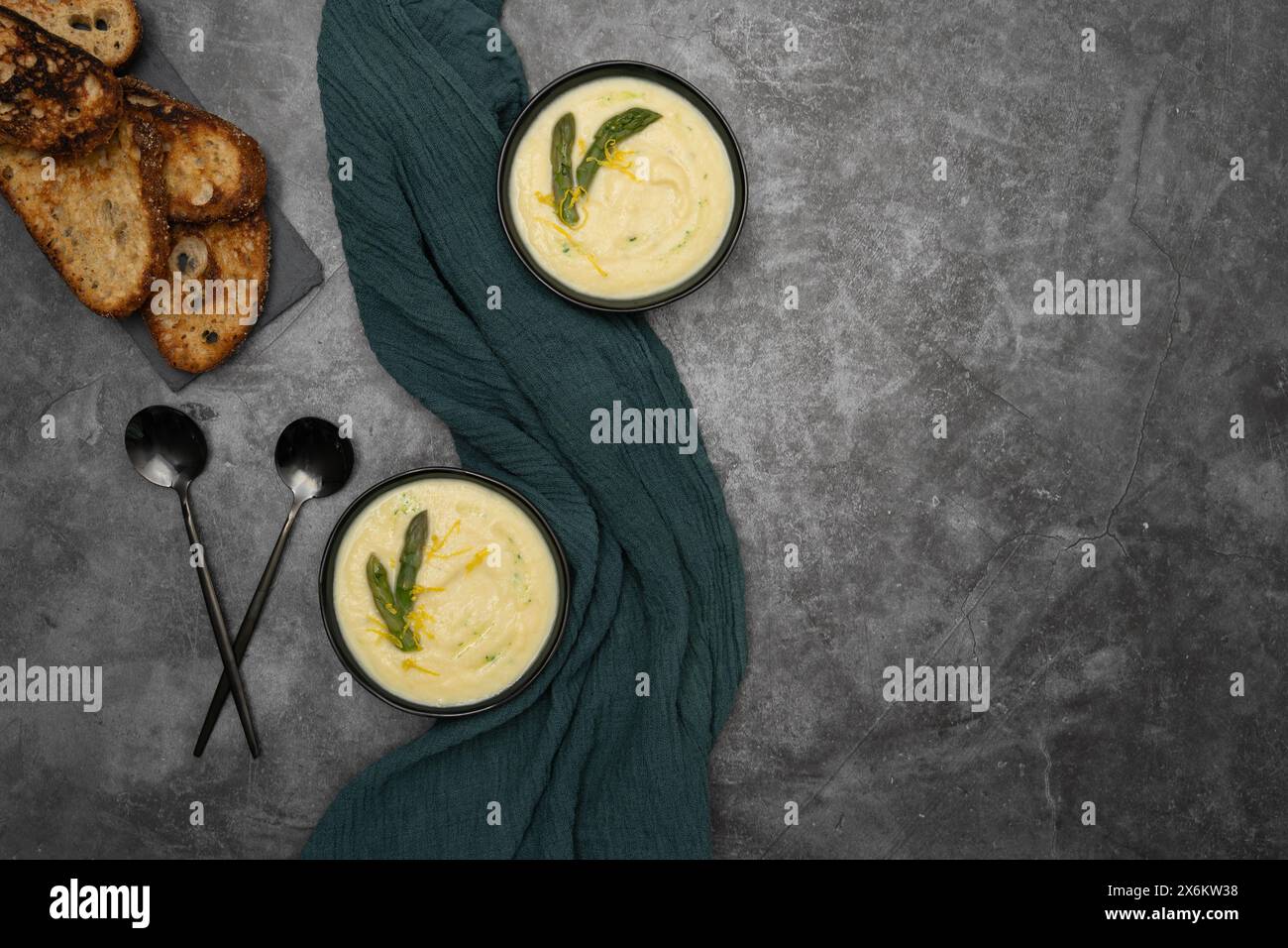 Set against a stone gray background, two bowls of creamy spargel soup ...