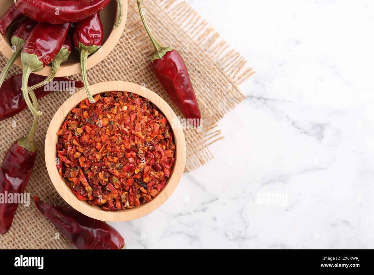 Chili pepper flakes and pods on white marble table, top view. Space for ...