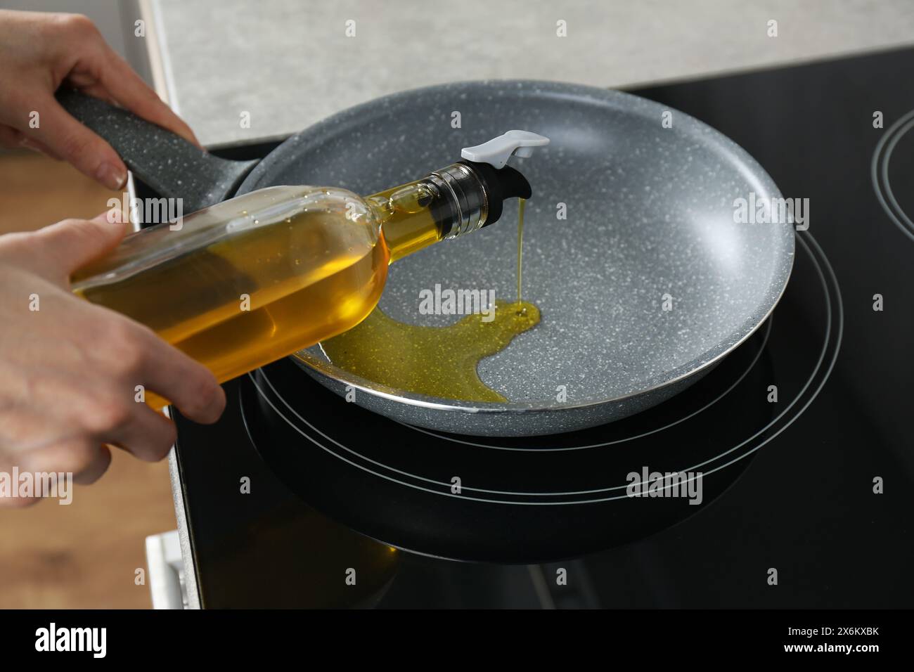 Vegetable fats. Woman pouring cooking oil into frying pan on stove ...