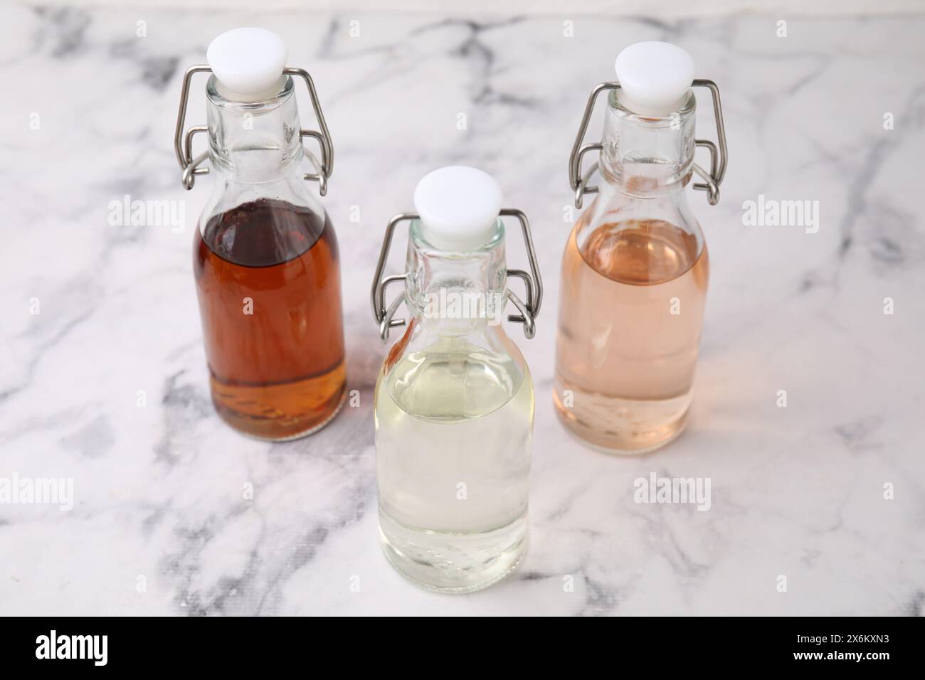 Different types of vinegar in bottles on light marble table, closeup ...