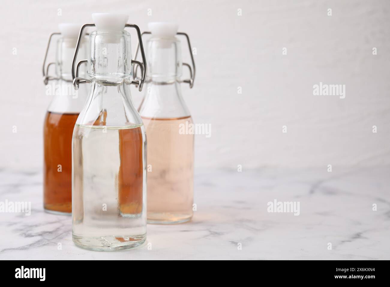 Different types of vinegar in bottles on light marble table, closeup ...