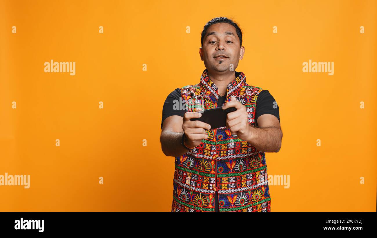 Happy Indian man entertained by videogames on smartphone, enjoying ...