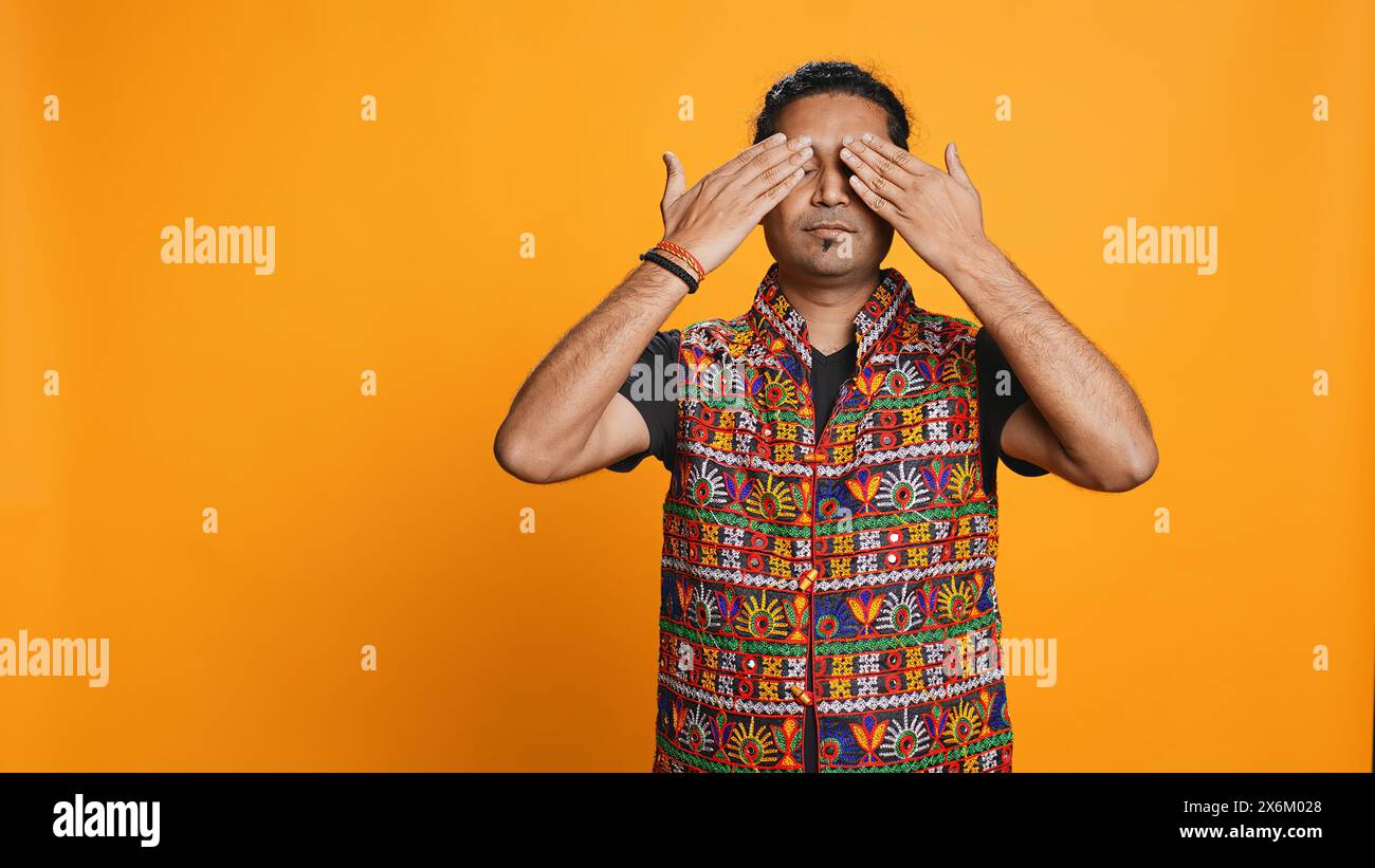 Man wearing traditional indian clothing covering eyes, ears and mouth ...
