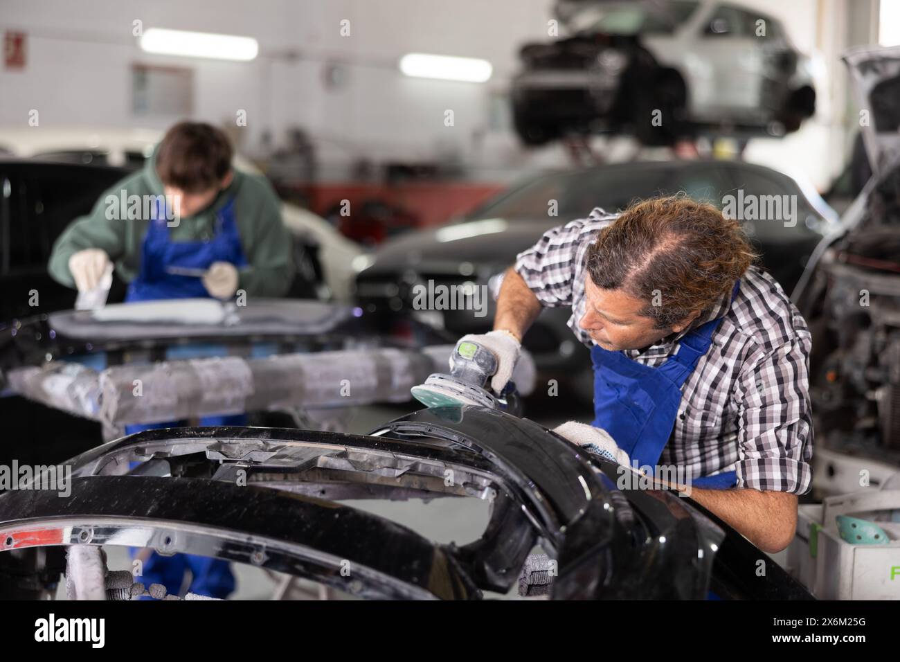 Man prepares car for painting in workshop - using grinding machine he ...