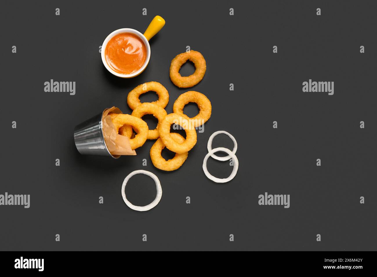 Metal bucket with fried breaded onion rings and sauce on black ...