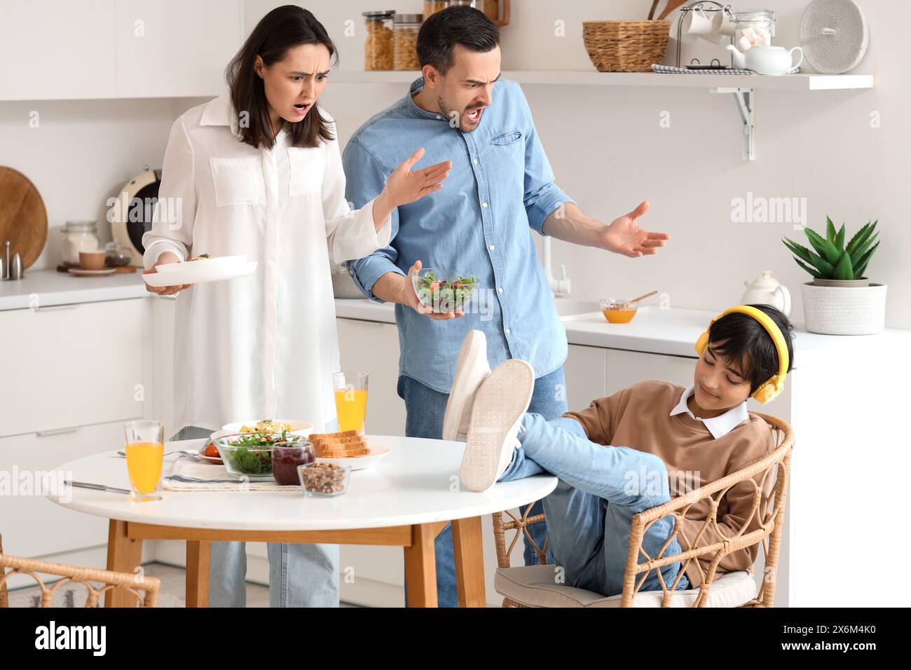 Teenage boy with his feet on table and angry parents during dinner in ...
