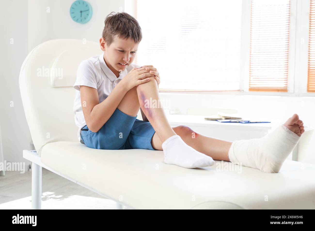 Little boy with injured leg sitting on couch in clinic Stock Photo - Alamy