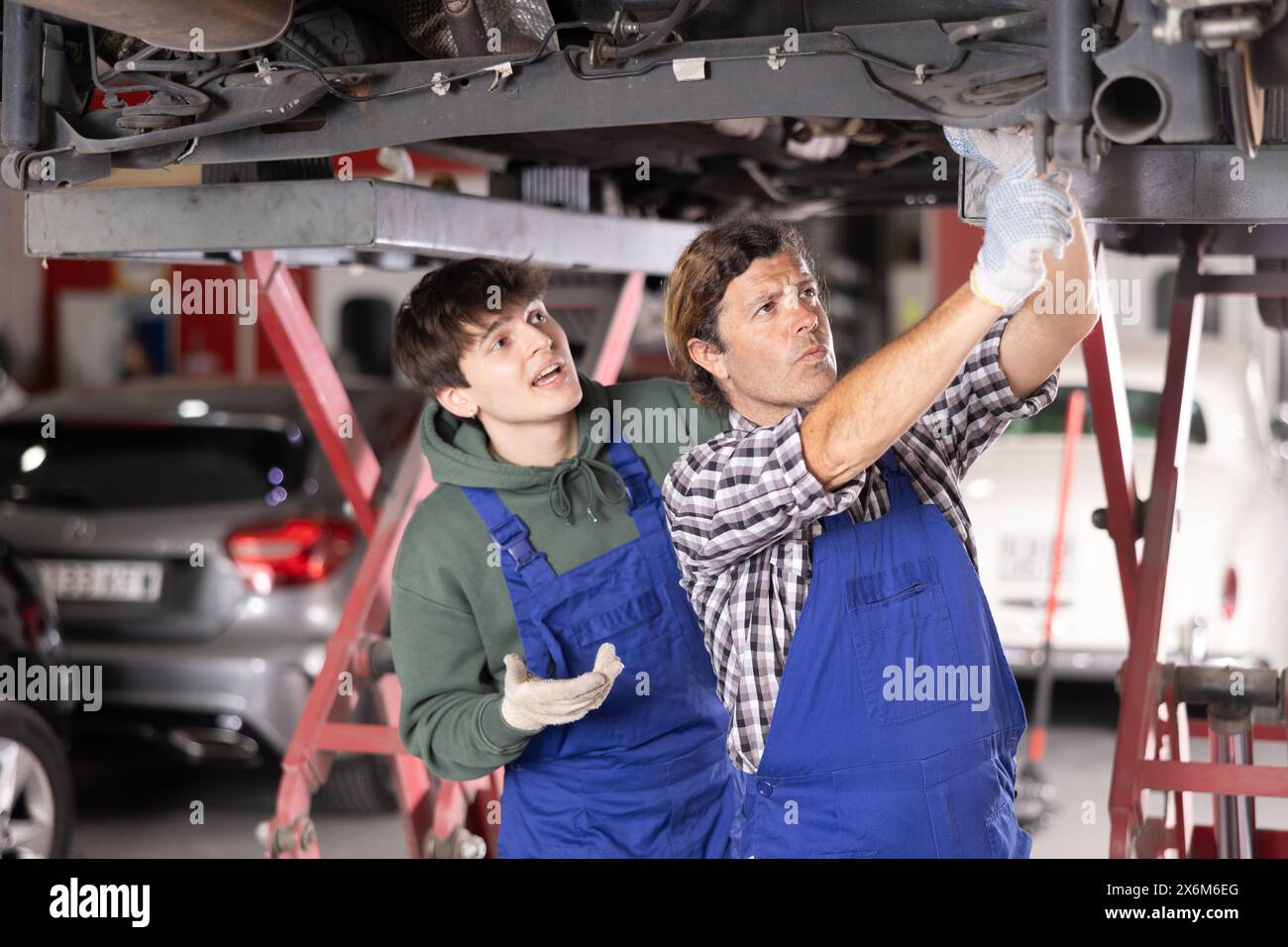 Guy and man mechanics repairing underbody of car Stock Photo - Alamy