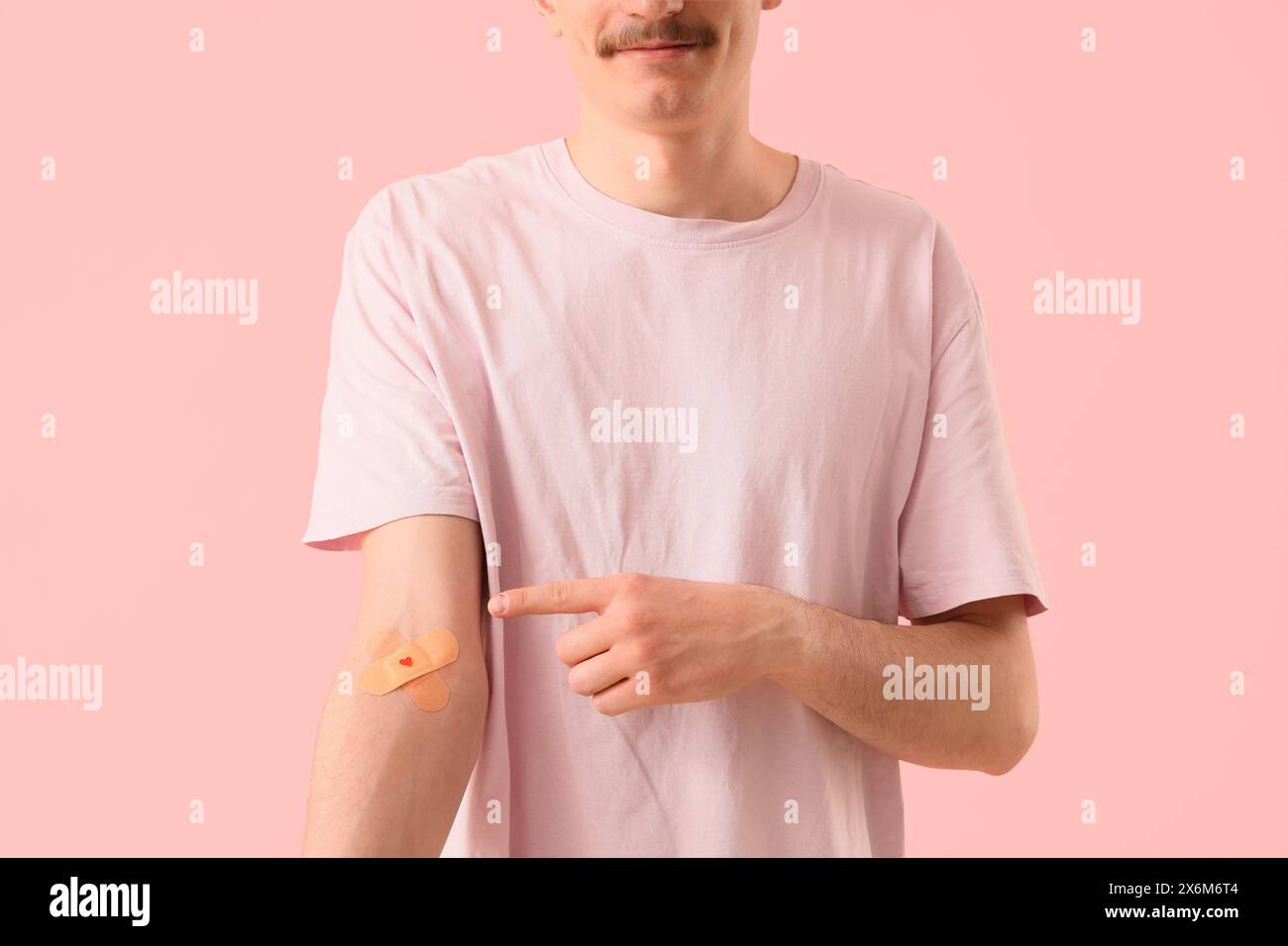 Male blood donor pointing at applied patches on pink background ...