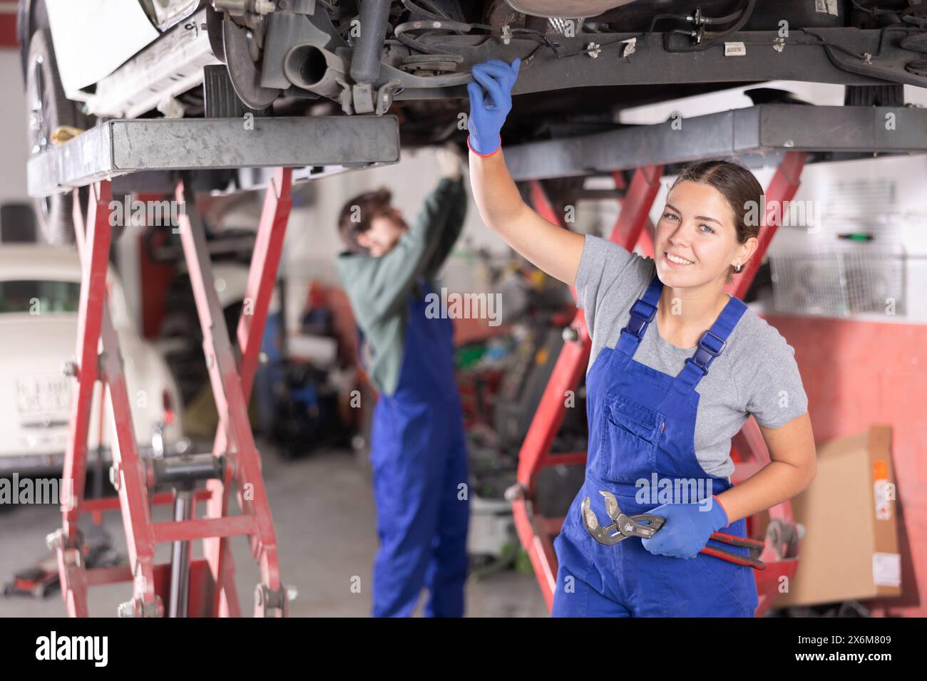 Female mechanic checking the rear suspension shock absorber of car ...
