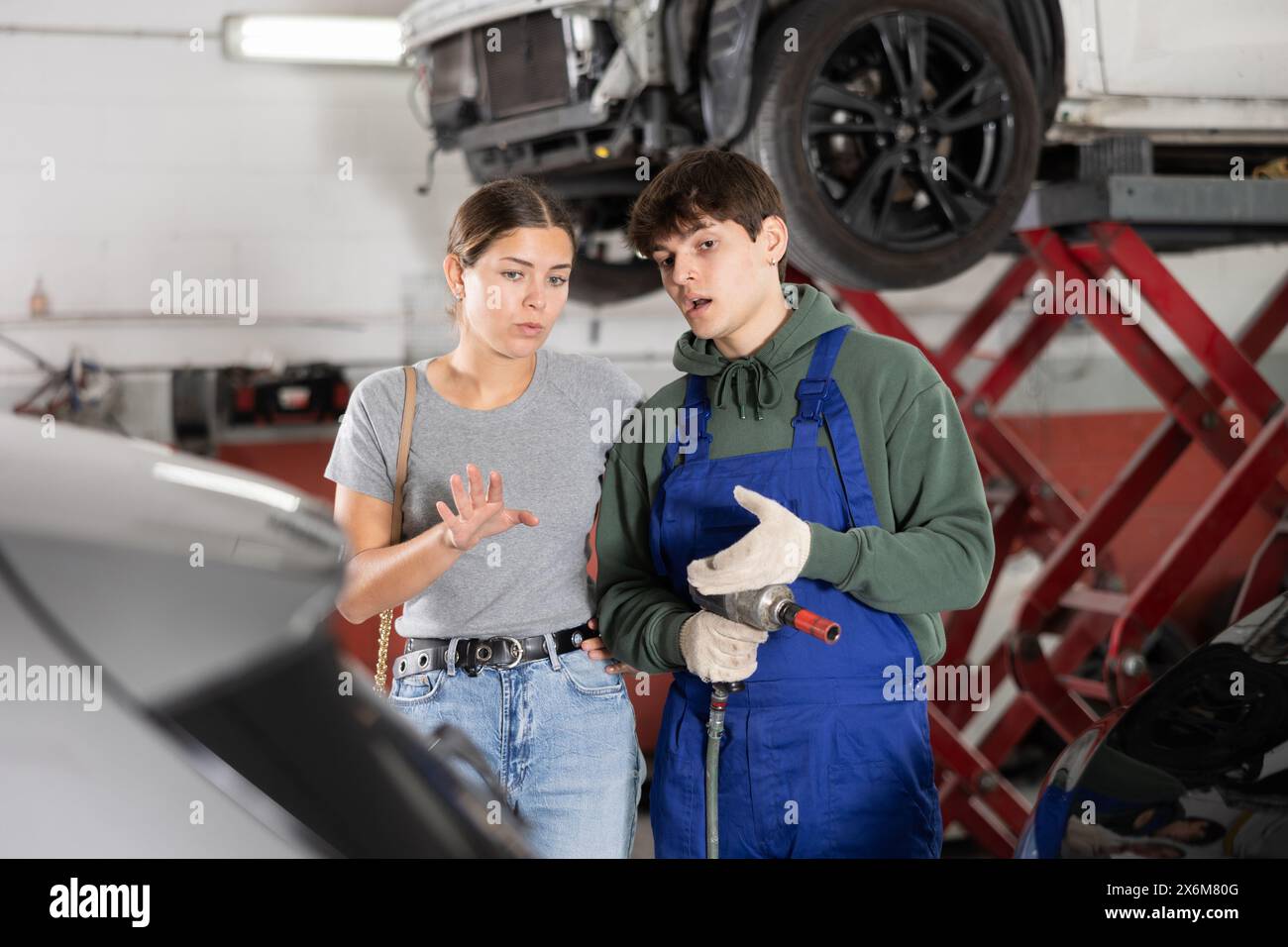 Guy car repair shop worker consulting woman client Stock Photo - Alamy