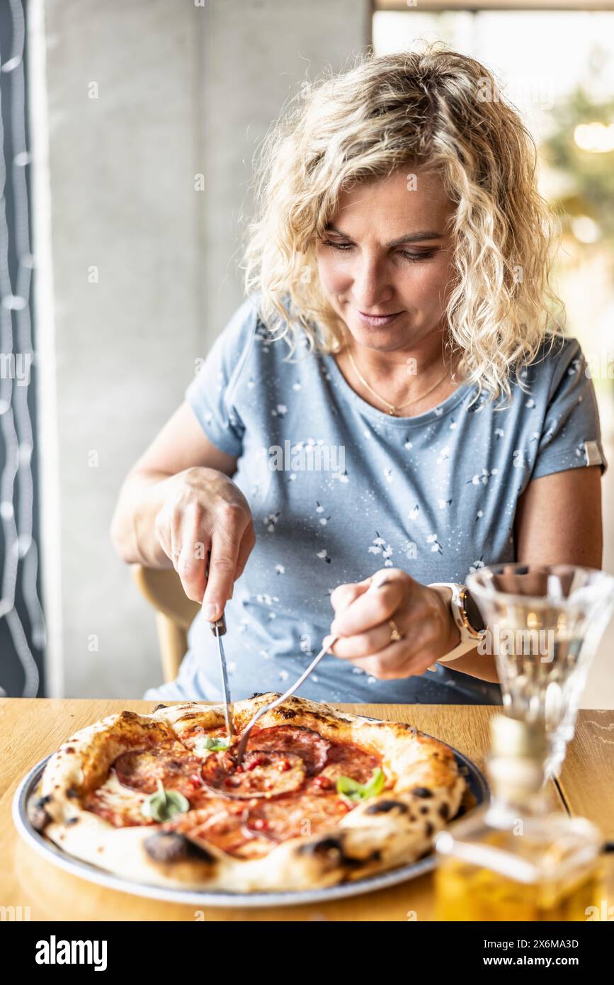 Woman eating spicy salami pizza Stock Photo - Alamy