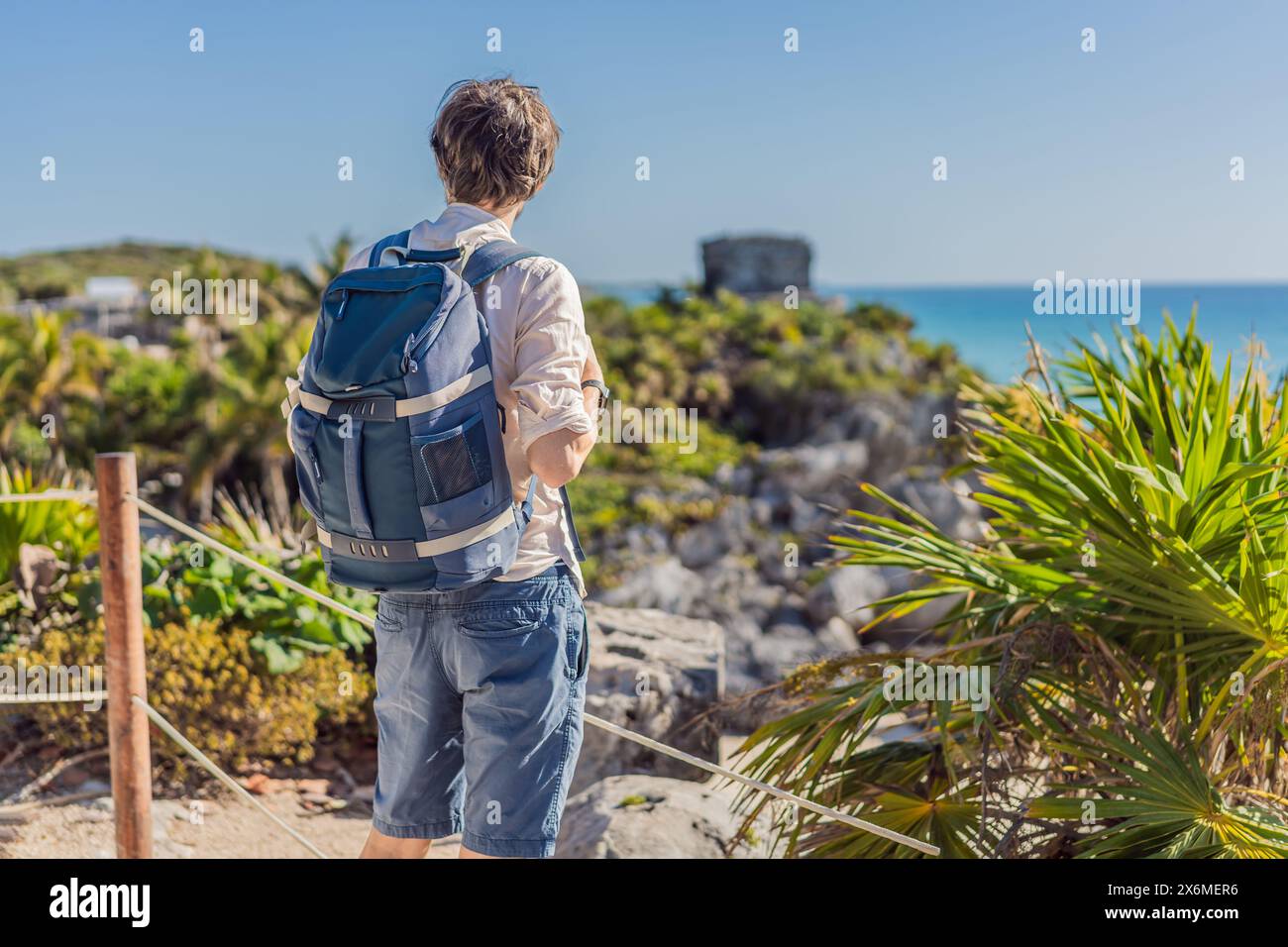 Man tourist enjoying the view Pre-Columbian Mayan walled city of Tulum ...
